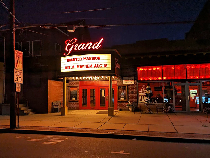 The iconic red neon "Grand" sign glows against the brick facade, announcing today's features with vintage flair that no digital display could match.