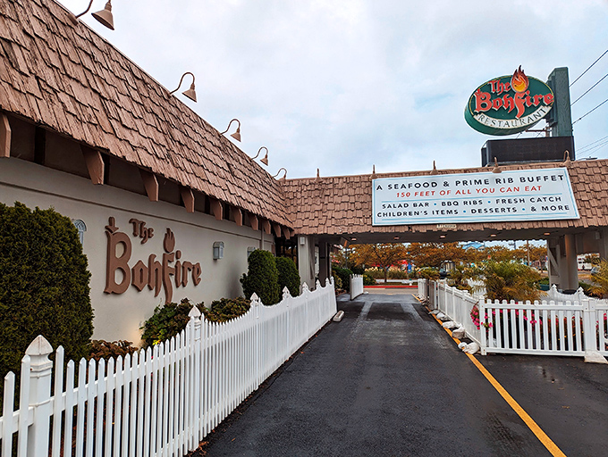 The iconic flame sign beckons hungry travelers like a coastal lighthouse, promising seafood treasures behind that rustic cedar shake exterior and charming white picket fence.