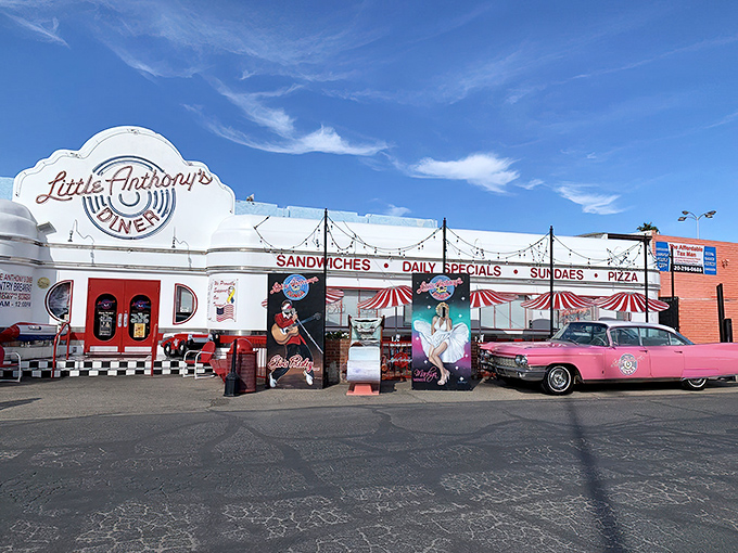 The gleaming white exterior of Little Anthony's Diner beckons like a time portal to the 1950s, complete with colorful retro chairs and classic car.