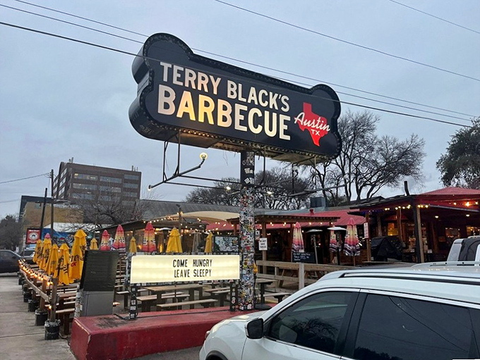 The neon BBQ sign glows like a smoky beacon of hope for hungry travelers. Terry Black's industrial-chic exterior promises no frills&mdash;just exceptional barbecue worth the journey.