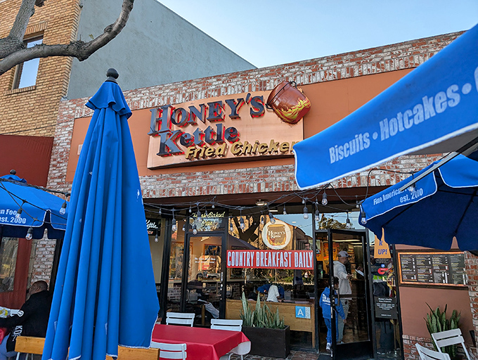 The bright blue awning beckons like a lighthouse for hungry souls. Honey's Kettle's warm brick exterior promises comfort food that delivers on its "Fine American Food" declaration.