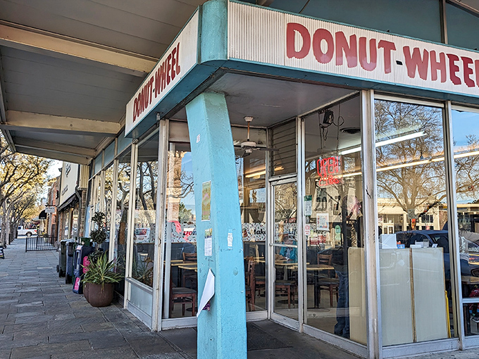 The glowing Donut Wheel sign beckons like a sugary lighthouse in the night. Simple, unpretentious, and promising sweet perfection inside.