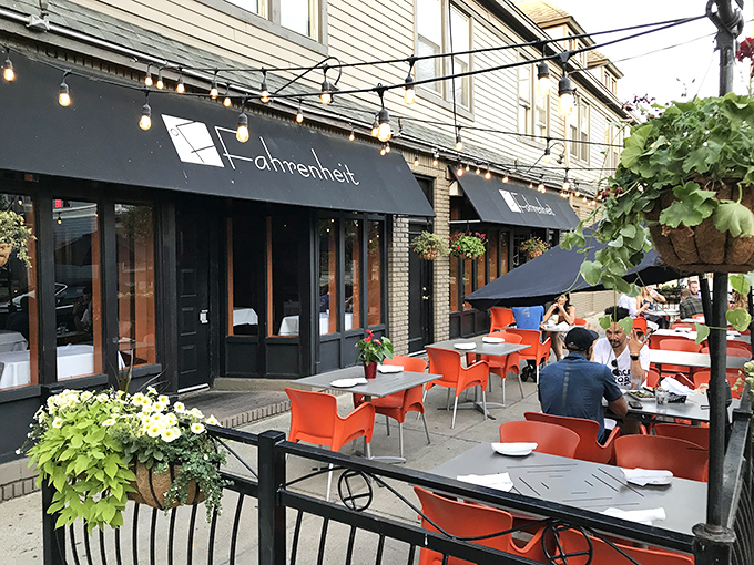 Fahrenheit's charming patio beckons with vibrant orange tables and lush greenery, creating a sidewalk oasis in Cleveland's Tremont neighborhood.