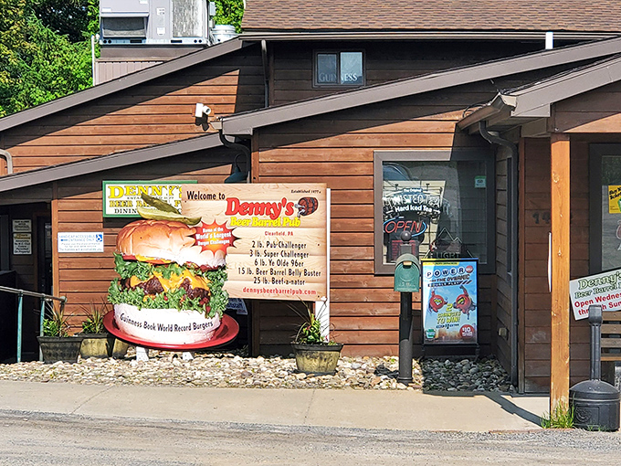 The rustic wooden exterior of Denny's Beer Barrel Pub promises burger adventures within, with a sign proudly displaying their legendary food challenges.