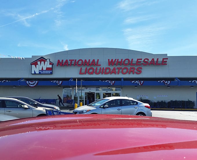 The iconic red signage of National Wholesale Liquidators beckons bargain hunters like a retail lighthouse guiding ships to discount shores.