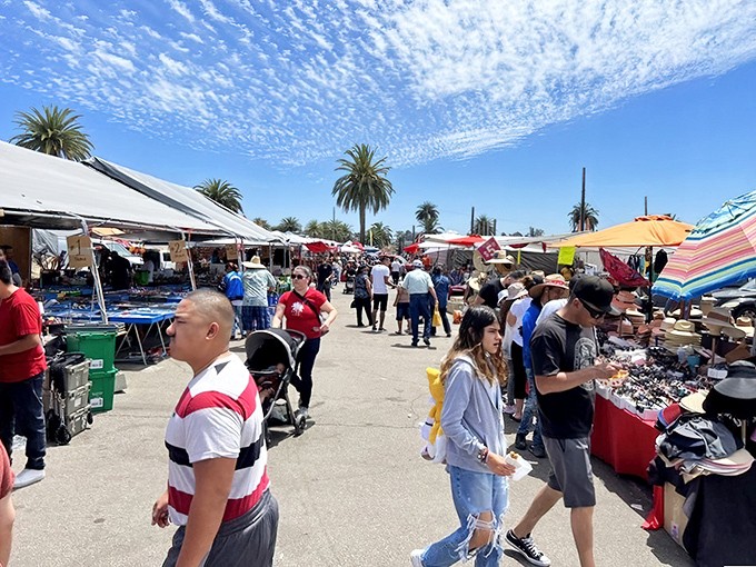 Palm trees stand sentinel over a bustling marketplace where treasure hunters navigate rows of canopies, each aisle promising undiscovered gems and unexpected bargains.