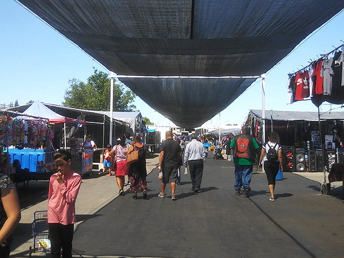 The bustling heart of Stockton's flea market, where green canopies create a microclimate of commerce and the hunt for treasures begins.