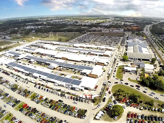 From above, the sprawling Fleamasters Flea Market stretches across the landscape, a maze of vendor stalls framed by Florida palm trees — a true bargain hunter’s paradise seen from the sky.