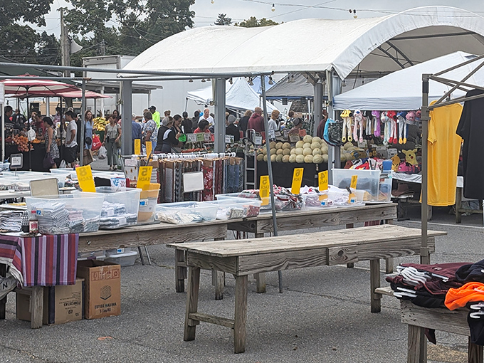 The bustling heart of Root's Old Mill Flea Market, where treasure hunters navigate a sea of possibilities under white canopy tents.