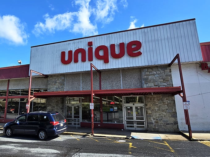 The iconic red "unique" sign beckons bargain hunters like a retail lighthouse, promising treasures within those unassuming walls.
