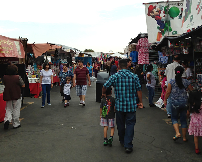 The human river of bargain hunters flows between colorful stalls at Paramount Swap Meet, where shopping transforms from errand to adventure.
