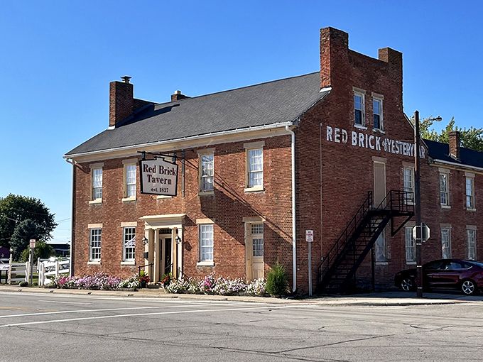 The historic Red Brick Tavern stands proudly along Route 40, its weathered facade a testament to nearly two centuries of serving hungry travelers since 1837. 