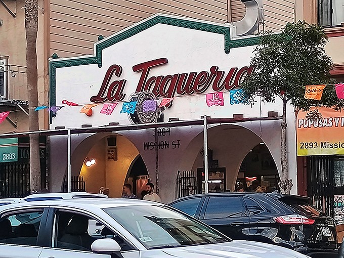 The iconic white facade with red script signage stands like a beacon of burrito brilliance on Mission Street, colorful papel picado dancing in the San Francisco breeze.
