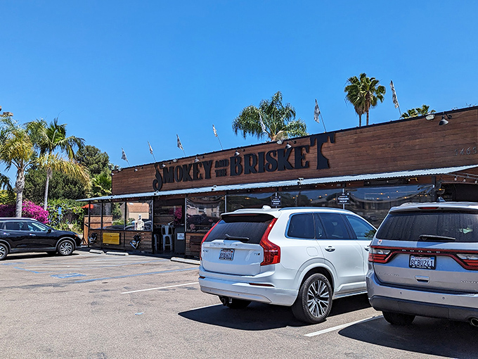The wooden facade of Smokey and The Brisket stands like a barbecue beacon under the California sun, palm trees swaying as if drawn by the smoky aroma.