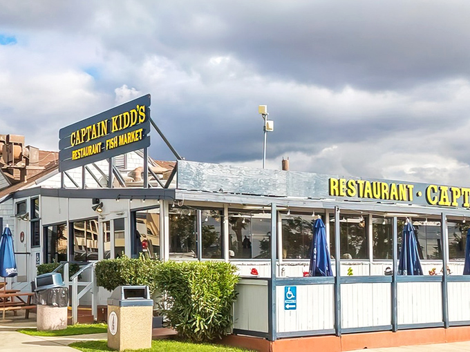 The blue-and-white striped awning of Captain Kidd's stands like a maritime beacon, promising seafood treasures within. Palm trees sway in agreement.