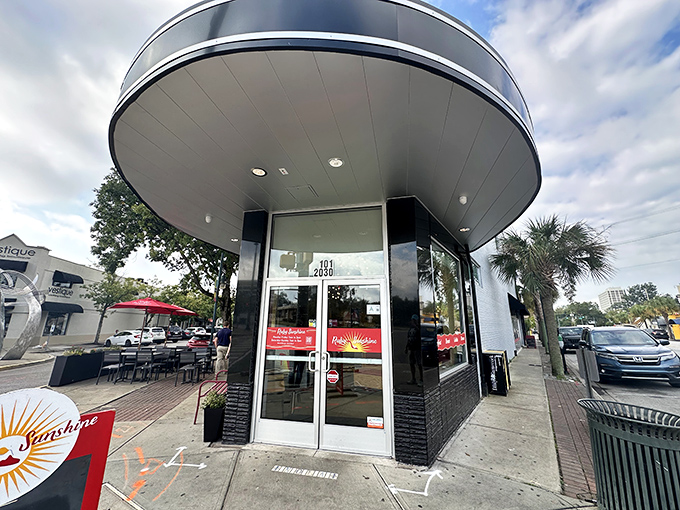 The sleek, modern entrance to Ruby Sunshine beckons like a breakfast lighthouse, promising morning salvation with its distinctive curved architecture.