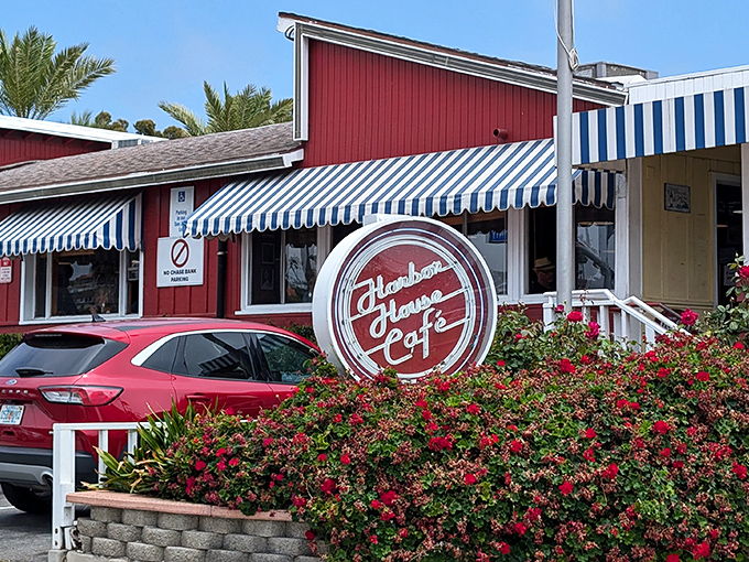The iconic red exterior with blue-striped awnings stands like a culinary lighthouse on PCH, beckoning hungry travelers with promises of comfort food perfection.