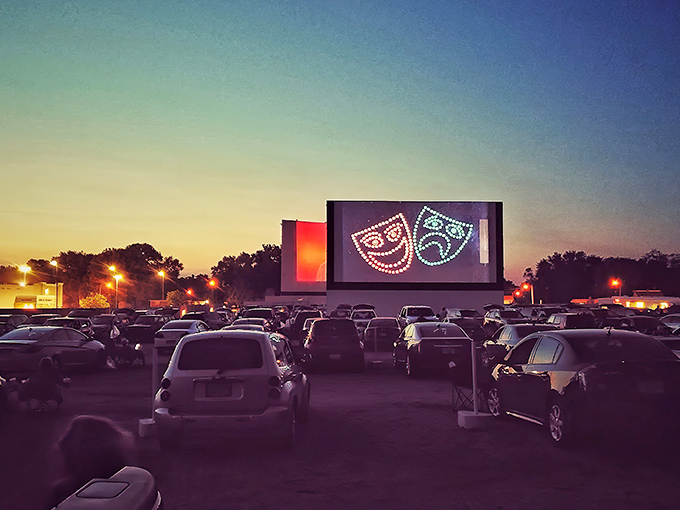 Twilight magic at its finest&mdash;cars gathered under a darkening sky as comedy and tragedy masks illuminate the massive screen at Skyview Drive-In.