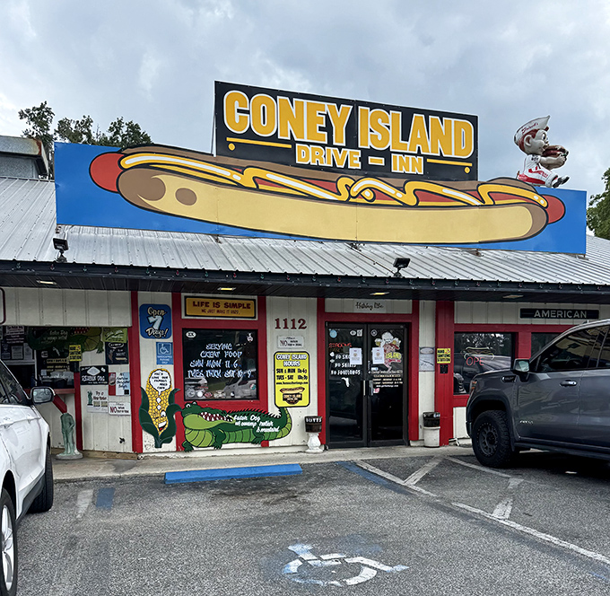 The bright yellow exterior of Coney Island Drive Inn stands out like a beacon of comfort food, complete with that iconic hot dog mascot keeping watch.