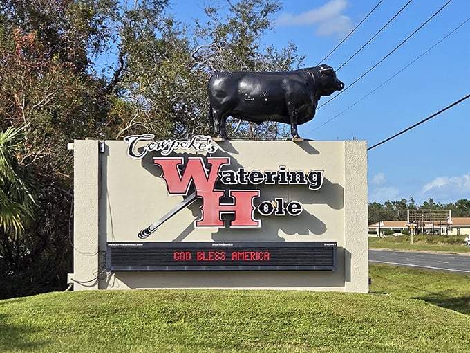 The iconic red signage of Cowpoke's Watering Hole beckons hungry travelers like a lighthouse for the famished. This unassuming exterior hides culinary treasures within. 
