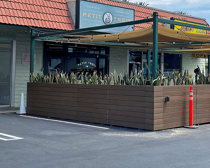 The sidewalk patio at Petit Trois offers a slice of Parisian caf&eacute; culture right on Highland Avenue. Red signage announces this culinary gem to those lucky enough to be in the know.