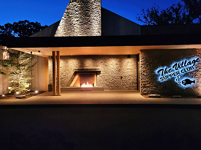 The stone facade of Village Supper Club stands like a modern castle of cuisine, welcoming hungry travelers with its distinctive peaked roof and warm lighting.