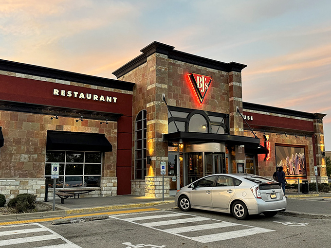 The stone and brick exterior of BJ's glows like a beacon at dusk, promising comfort and culinary adventure to weary Polaris shoppers.