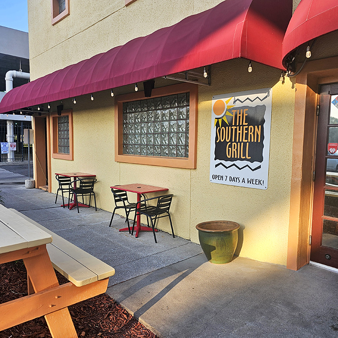 The welcoming exterior of The Southern Grill, with its signature red awning and outdoor seating, promises comfort food treasures within. Open seven days a week for your barbecue emergencies.