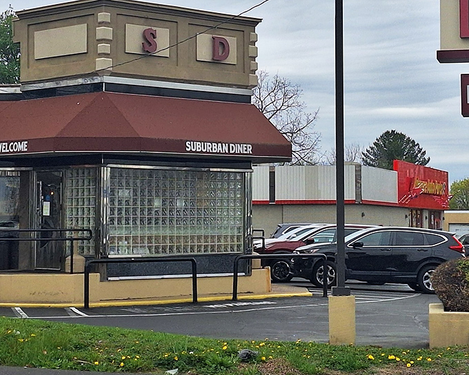 The burgundy awning and glass block windows of Suburban Diner stand as a beacon for hungry travelers. Classic roadside Americana at its finest.