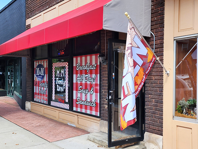 The unassuming storefront of M & M Family Diner beckons with its classic red chairs and checkered window display. Small-town charm at its finest.