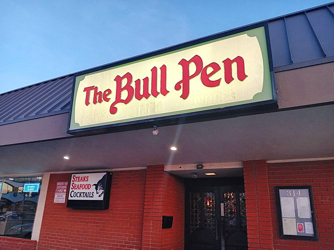 The iconic red lettering of The Bull Pen glows against the evening sky, a beacon for carnivores and cocktail enthusiasts alike.