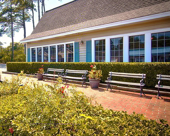 The charming yellow exterior of Lee's Inlet Kitchen glows at dusk, a beacon for seafood lovers with its Southern Living endorsement proudly displayed.