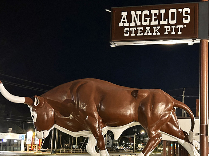 Big Gus stands sentinel outside Angelo's Steak Pit, a bovine ambassador promising carnivorous delights within. Like a meaty Statue of Liberty welcoming hungry masses. 