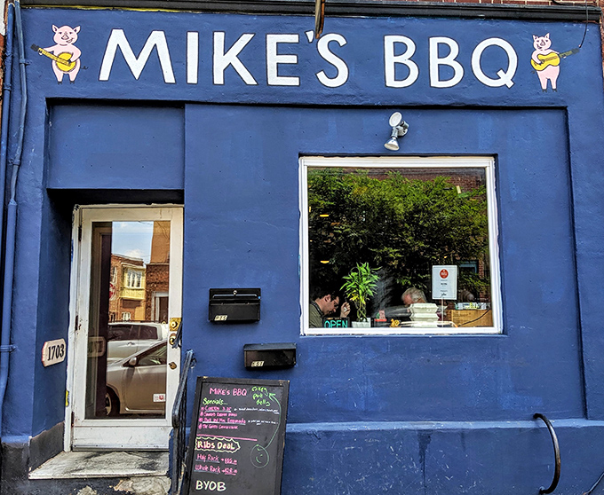 The blue storefront with cartoon pigs holding sandwiches says it all: serious barbecue served with a side of whimsy in South Philly.