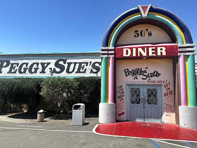 The rainbow-arched entrance to Peggy Sue's stands like a technicolor beacon in the desert, promising a time-traveling culinary adventure just off the highway.