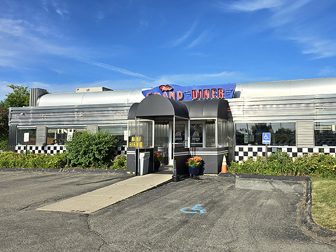 The gleaming silver exterior of The Grand Diner beckons like a time machine to the golden age of roadside Americana. Those checkered accents promise authentic diner magic inside.