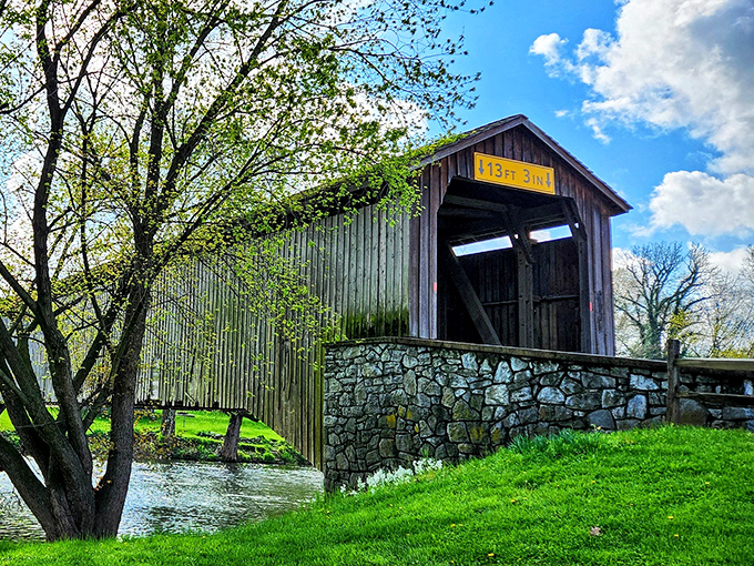 The timeless silhouette of Hunsecker's Mill Covered Bridge stands proudly against a blue Pennsylvania sky, its weathered boards telling stories of centuries past.