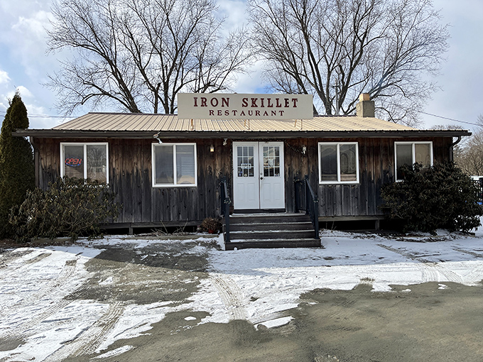 The unassuming wooden exterior of Iron Skillet stands like a culinary time capsule in Troy, promising comfort food treasures for those wise enough to stop.