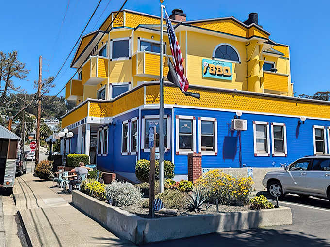 The sunshine-yellow and ocean-blue building stands like a beacon of barbecue hope on the coastline, promising smoky treasures within.