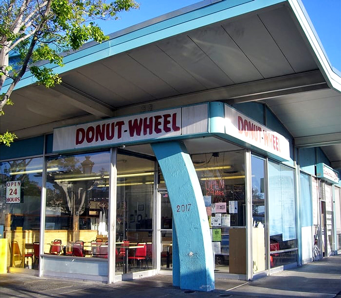 The iconic blue-pillared facade of Donut Wheel stands as a beacon of sweetness on Livermore's First Street, promising 24-hour donut salvation.
