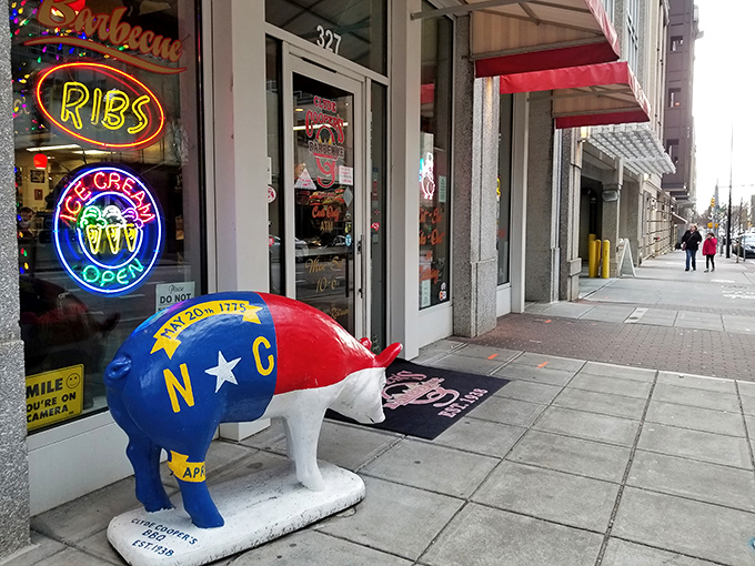 The iconic red-and-white storefront of Clyde Cooper's Barbeque stands as a beacon of hope for hungry souls in downtown Raleigh. That pig statue knows what you're in for.