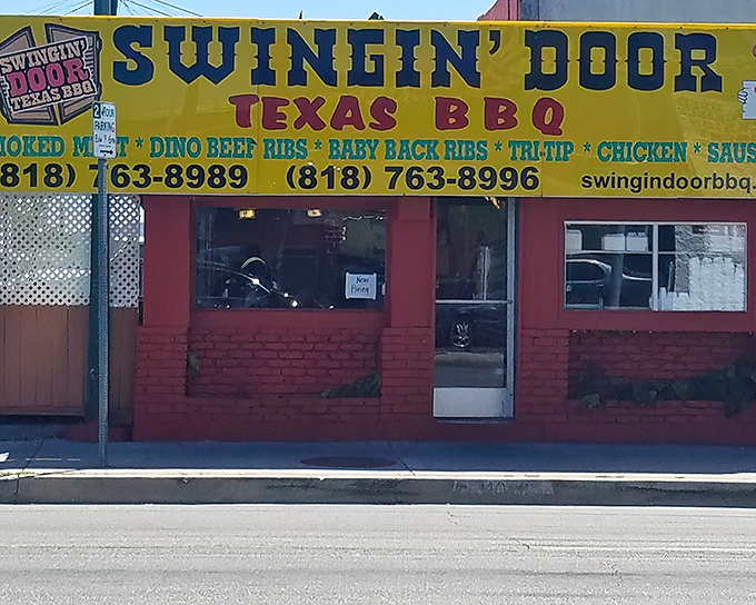 The bright red exterior with the vibrant yellow sign of Swingin' Door BBQ. isn't just eye-catching&mdash;it's a smoke signal to BBQ lovers that authentic Texas flavor awaits inside.