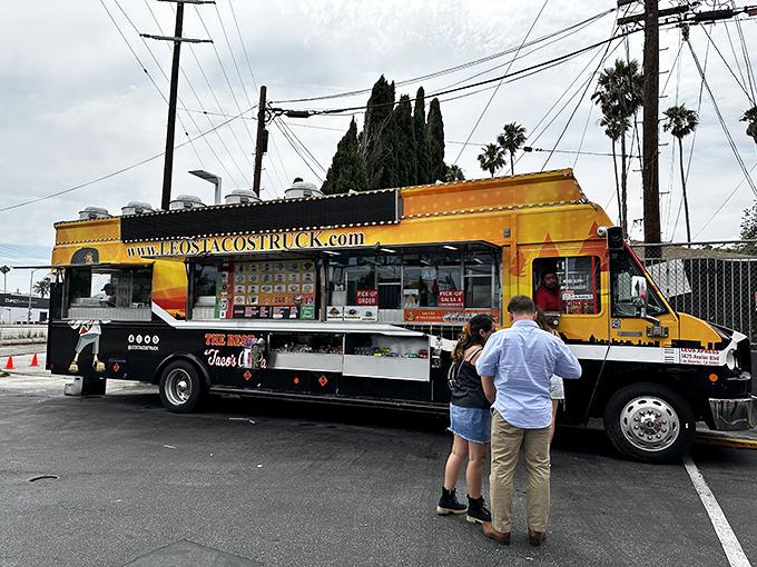The bright orange beacon of Leo's Tacos Truck stands ready for action, palm trees swaying overhead like nature's own welcome committee.