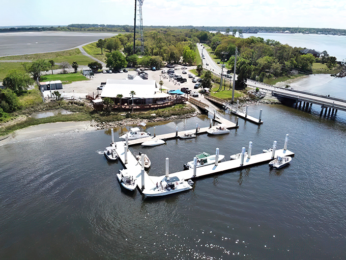 The blue-hued exterior of Palms Fish Camp Restaurant stands like a beacon for seafood lovers, with American flags fluttering above the wooden deck where waterfront dreams come true.