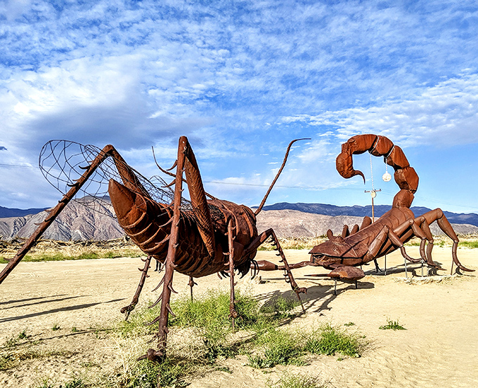 The dragon emerges from desert sands like a rusty leviathan, its metallic scales catching California sunlight while mountains stand guard in the distance.