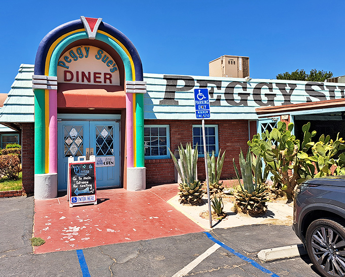 The rainbow-arched entrance to Peggy Sue's stands like a technicolor beacon in the desert, promising a time-traveling culinary adventure just off the highway.