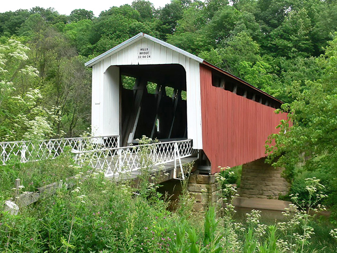 Nature's perfect frame for this classic red and white covered bridge, where the lush green hillsides of southeastern Ohio create a timeless postcard moment.