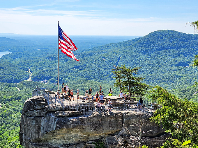 The iconic Chimney Rock juts dramatically from the mountainside, with visitors enjoying panoramic views that make your average selfie spot look like a kiddie pool.