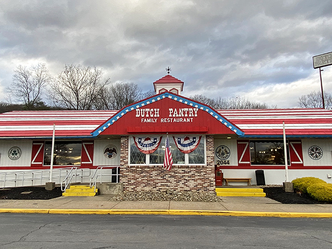 The red-roofed Dutch Pantry stands like a beacon of comfort food salvation along the Pennsylvania highway, promising homestyle goodness within those patriotic-trimmed walls.
