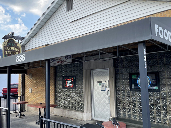 The unassuming exterior of Slyder's Tavern stands like a culinary speakeasy, its modest white siding and vintage sign promising delicious secrets within.